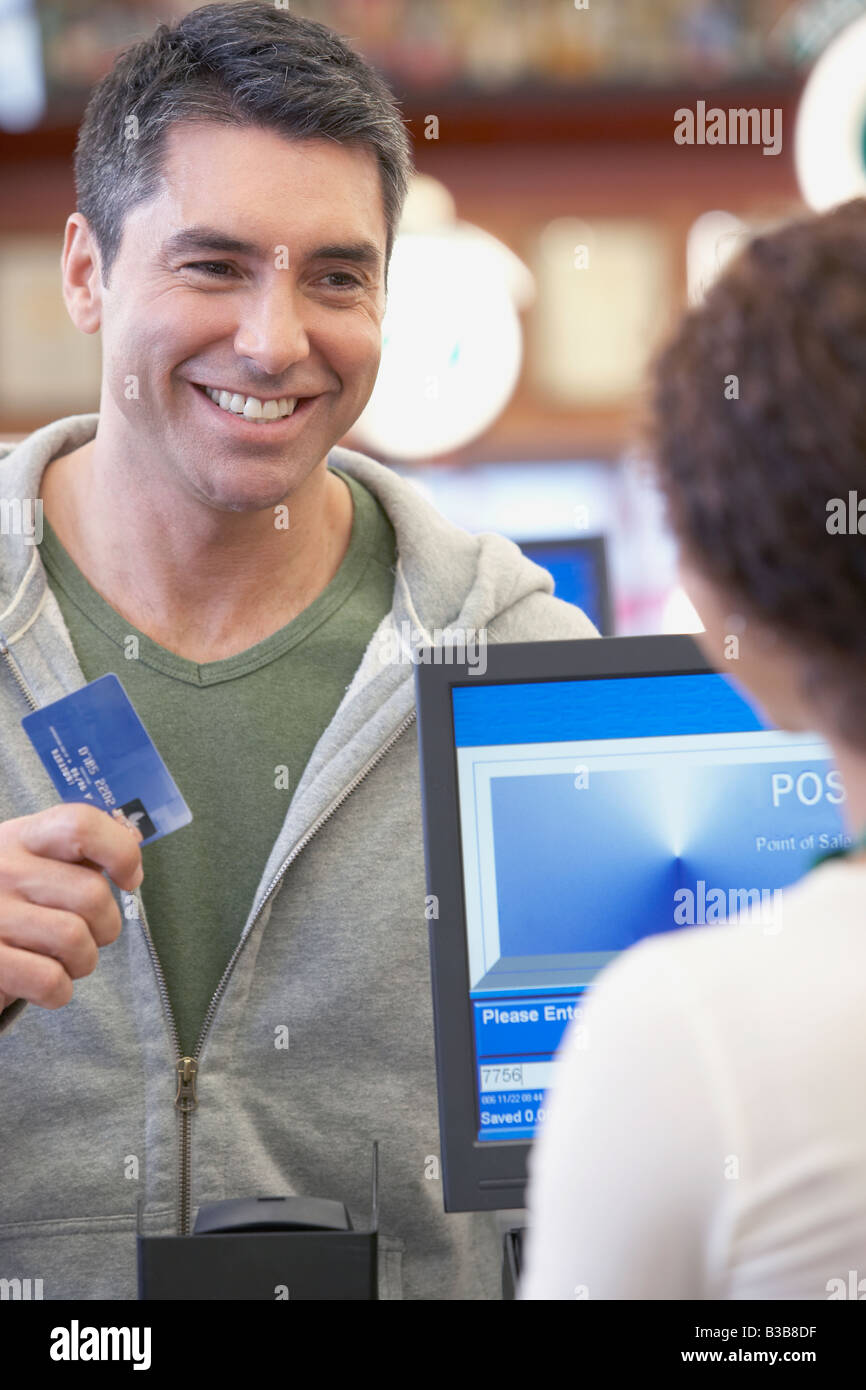 Hispanic man holding up credit card at check out Stock Photo - Alamy