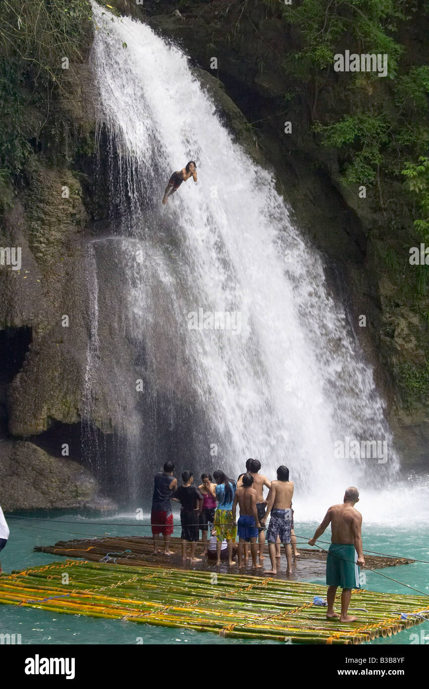 A diver jumps from the waterfall on the Kawasan River while tourists on ...
