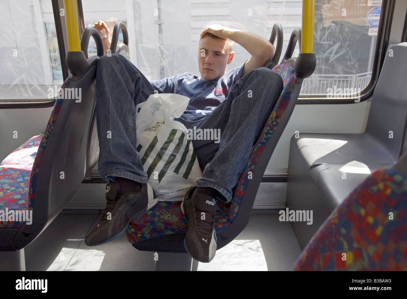 A young man looking thoughtful depressed whilst traveling on a bus ...