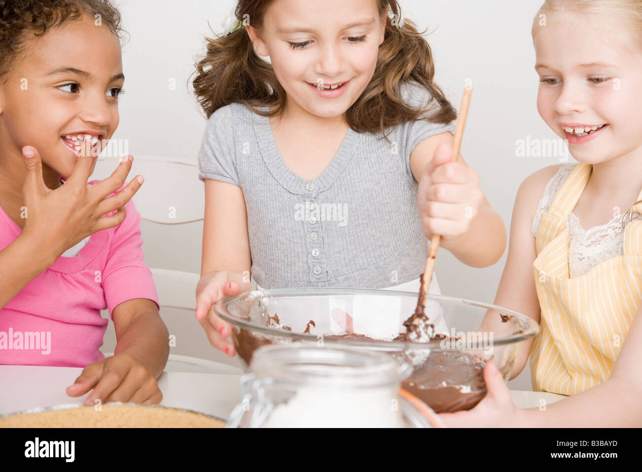 Multi-ethnic girls making batter Stock Photo - Alamy