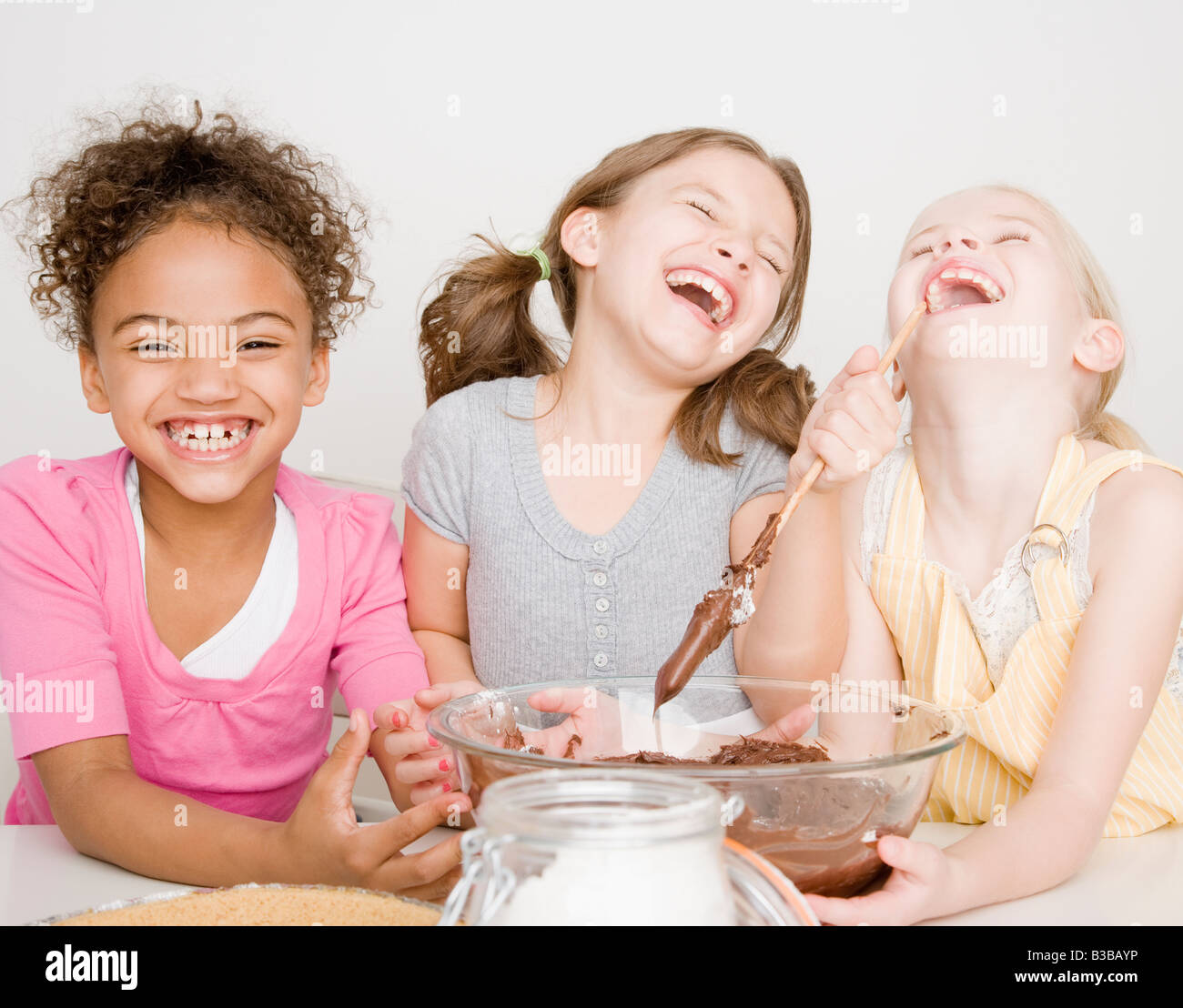 Multi-ethnic girls making batter Stock Photo - Alamy