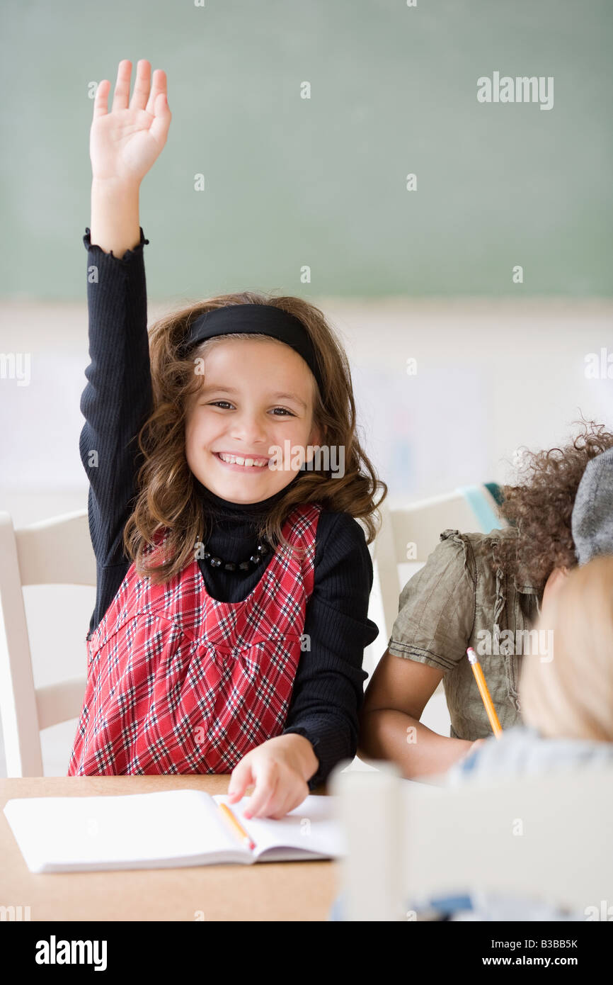 Girl raising hand in class Stock Photo - Alamy
