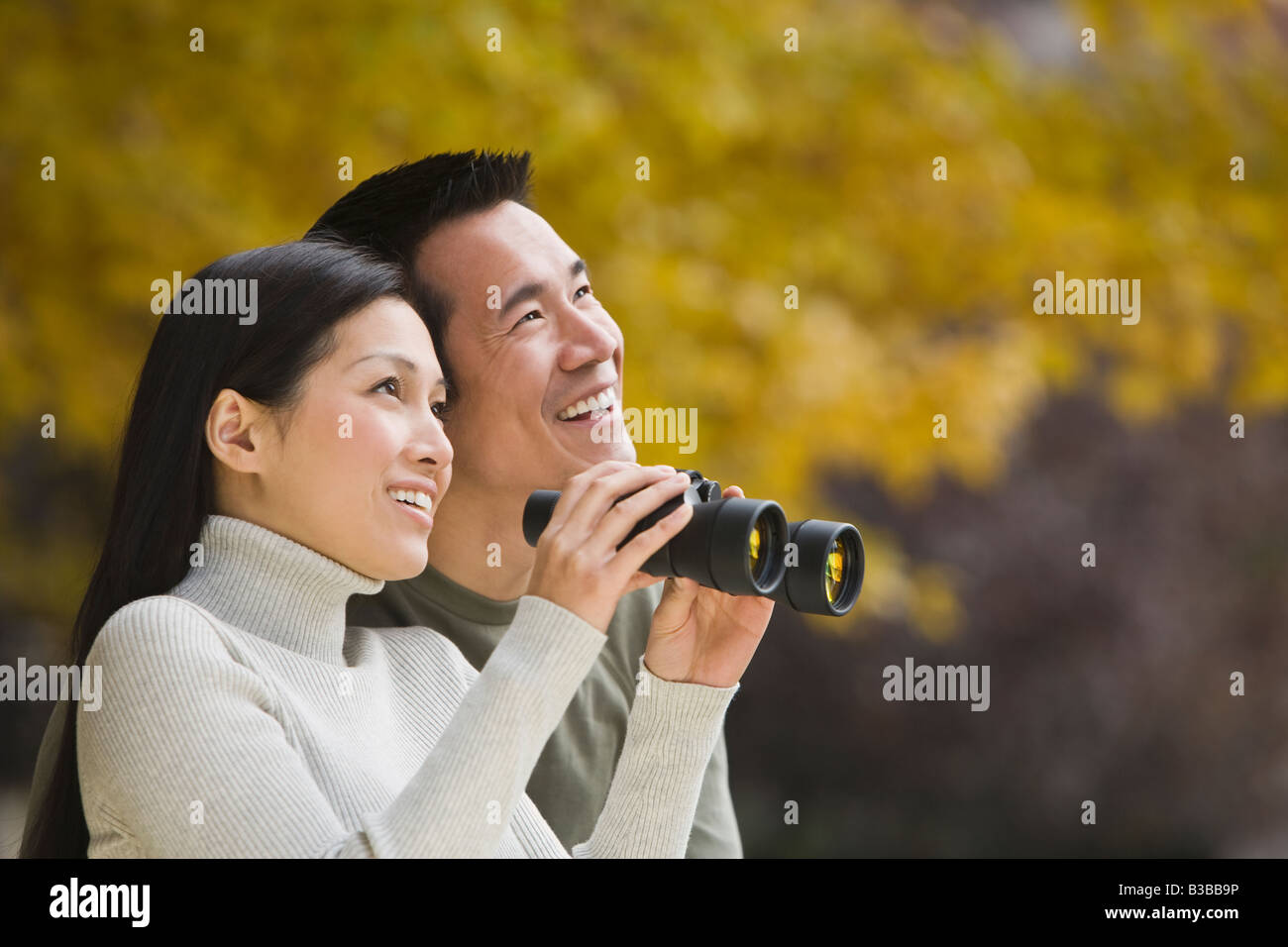Asian couple holding binoculars Stock Photo - Alamy