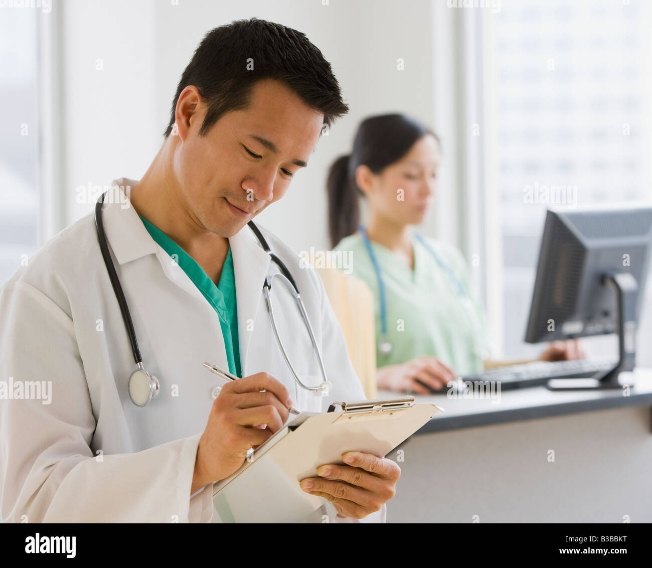 Asian male doctor writing on chart Stock Photo - Alamy