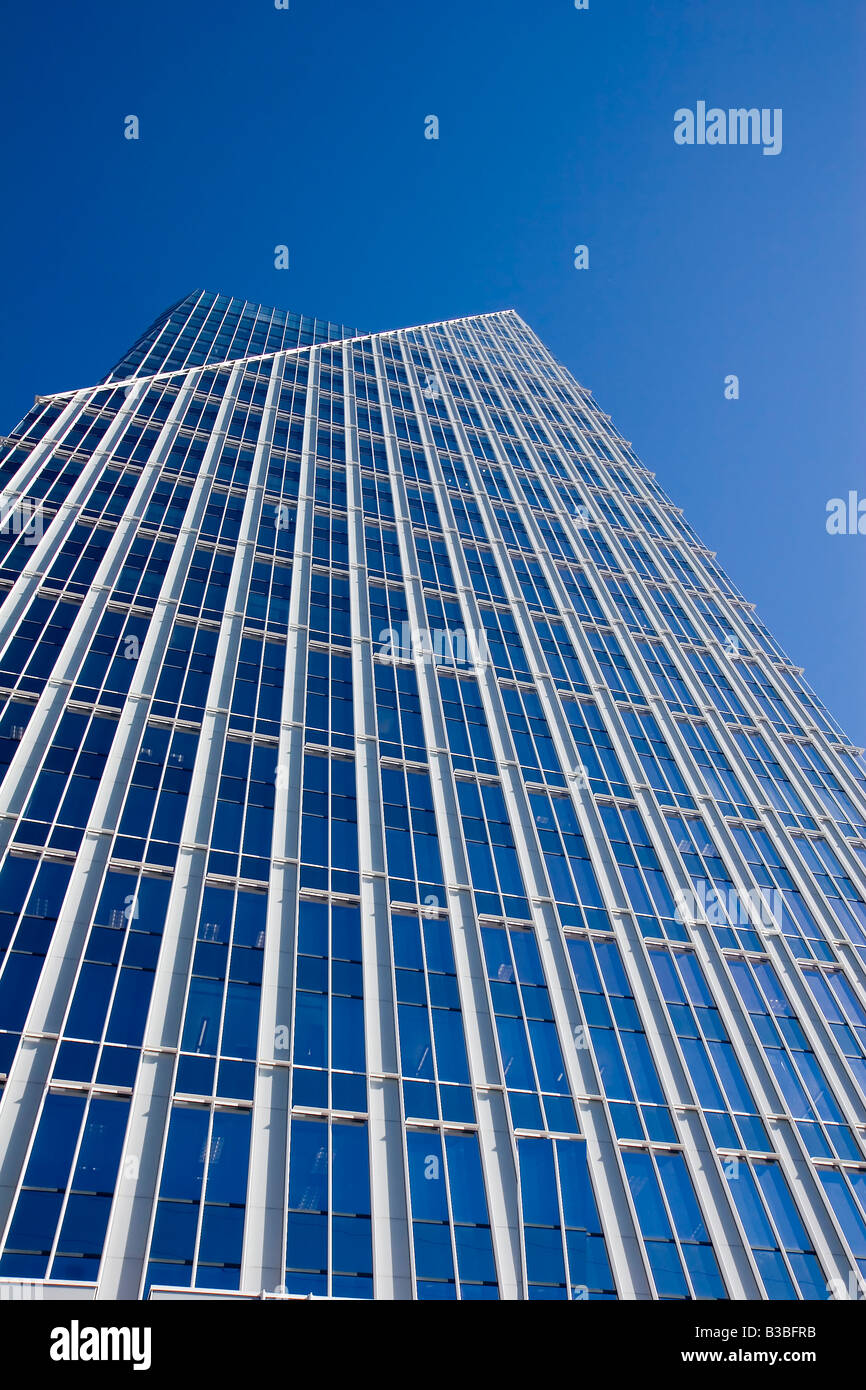 A modern high rise office tower with blue glass windows and blue sky ...