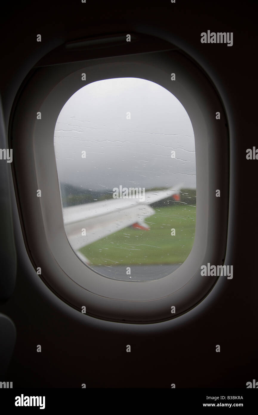 Looking out an aircraft window at the wing of a boeing 737 800 at rain ...