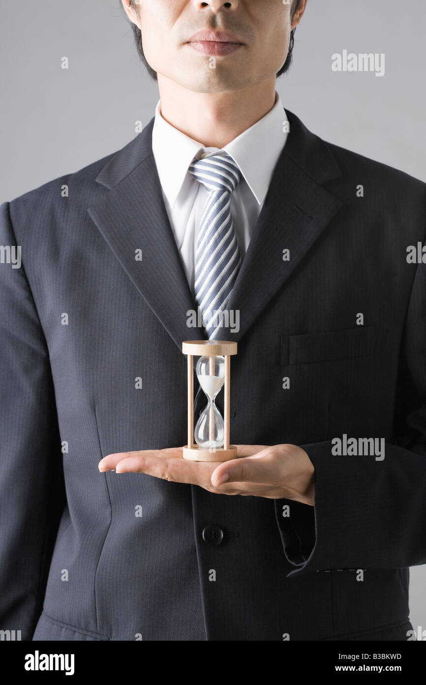 Businessman holding sand clock Stock Photo - Alamy