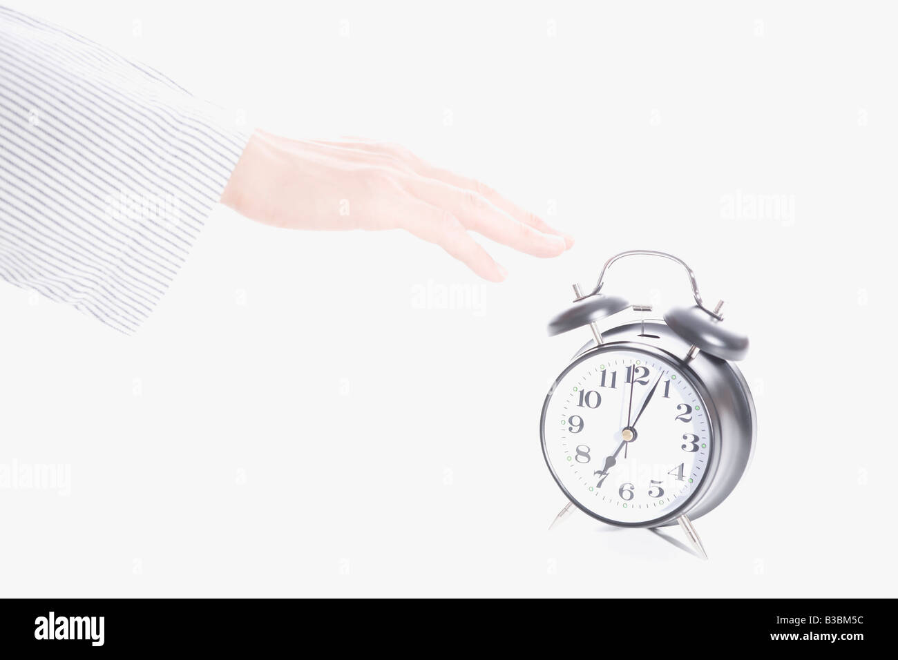 Hand reaching for alarm clock Stock Photo - Alamy