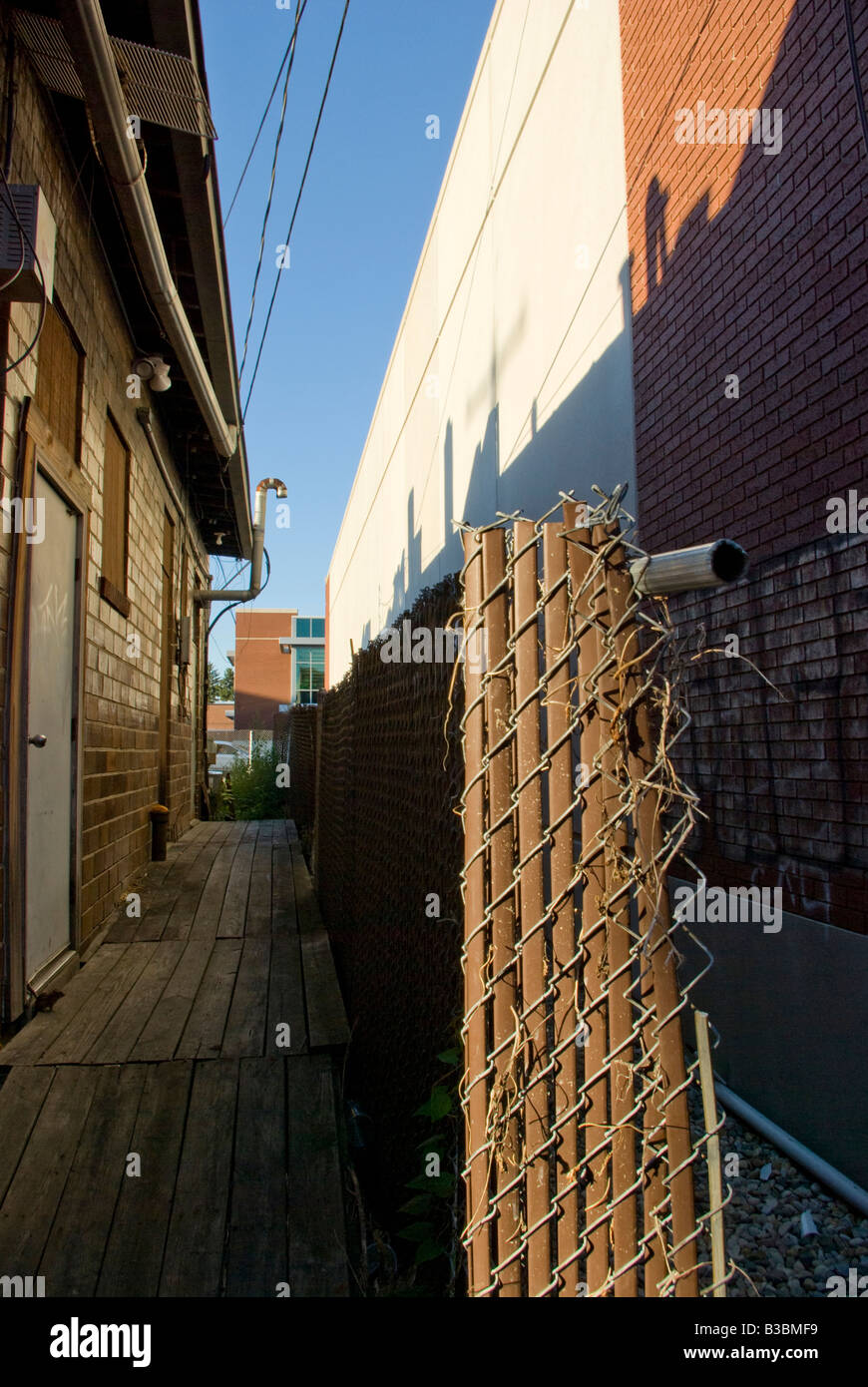 Rolled up temporary fencing sits in an alley behind new construction in ...