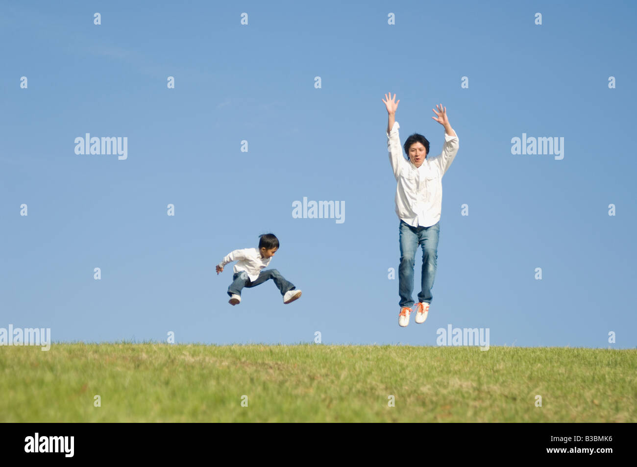 Father and son jumping on grass Stock Photo - Alamy