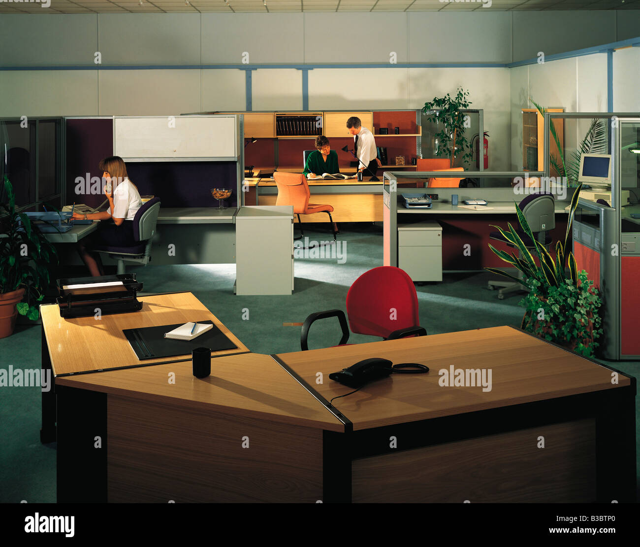 Office interior with empty desk and people working in background Stock ...