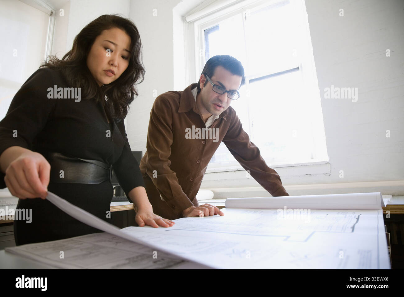 Multi-ethnic businesspeople looking at blueprints Stock Photo - Alamy