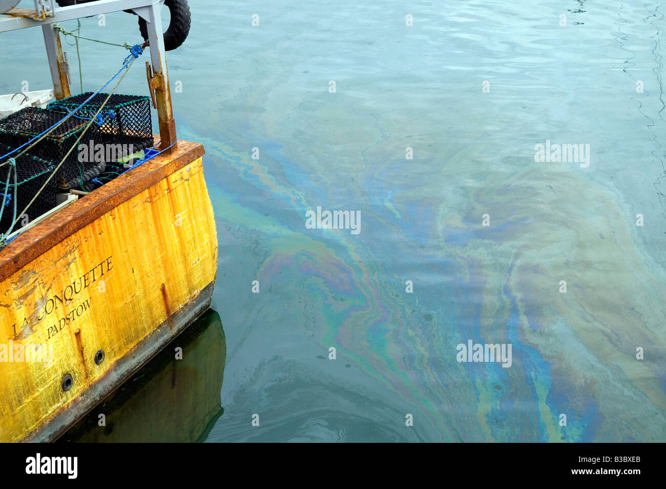 Coloured pattern of oil floating on the water and the back of a fishing ...