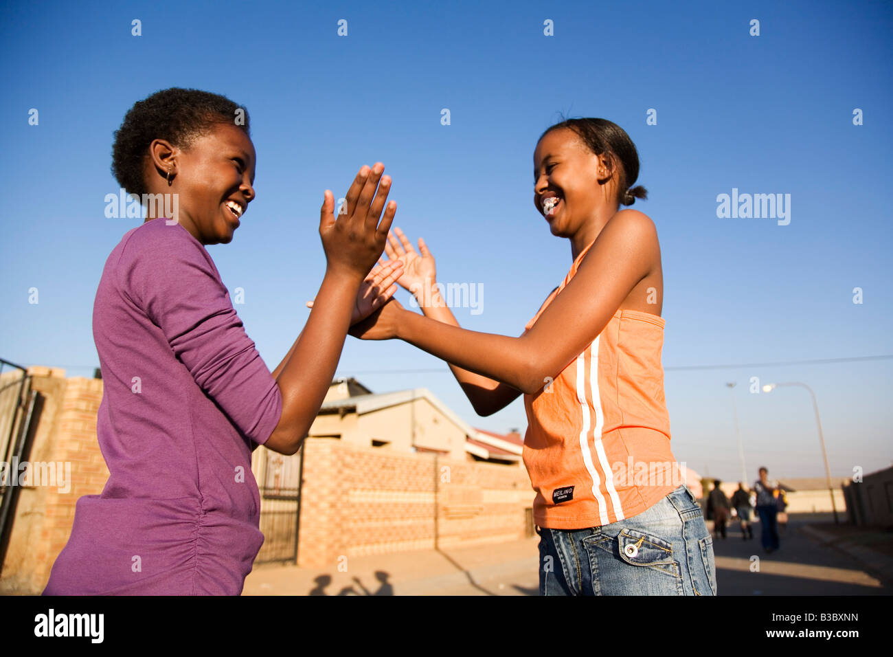 Two girls clapping hands, smiling, side view Stock Photo - Alamy