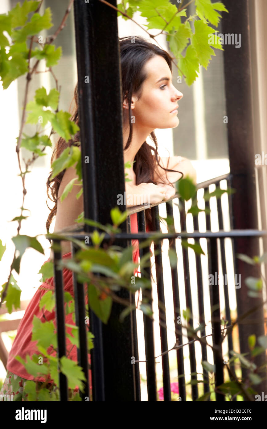 A young woman looking over balcony railings Stock Photo - Alamy
