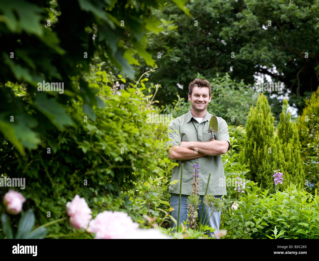 A man standing in a garden with a trowel Stock Photo - Alamy