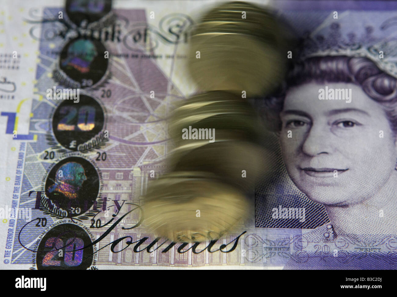 £1 coins rolling over a £20 note Stock Photo - Alamy