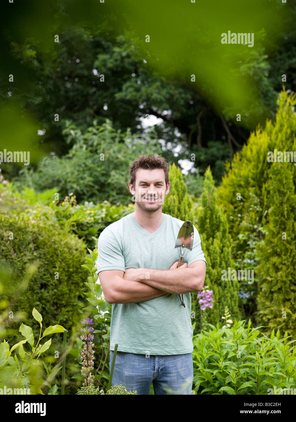 A man standing in a garden with a trowel Stock Photo - Alamy