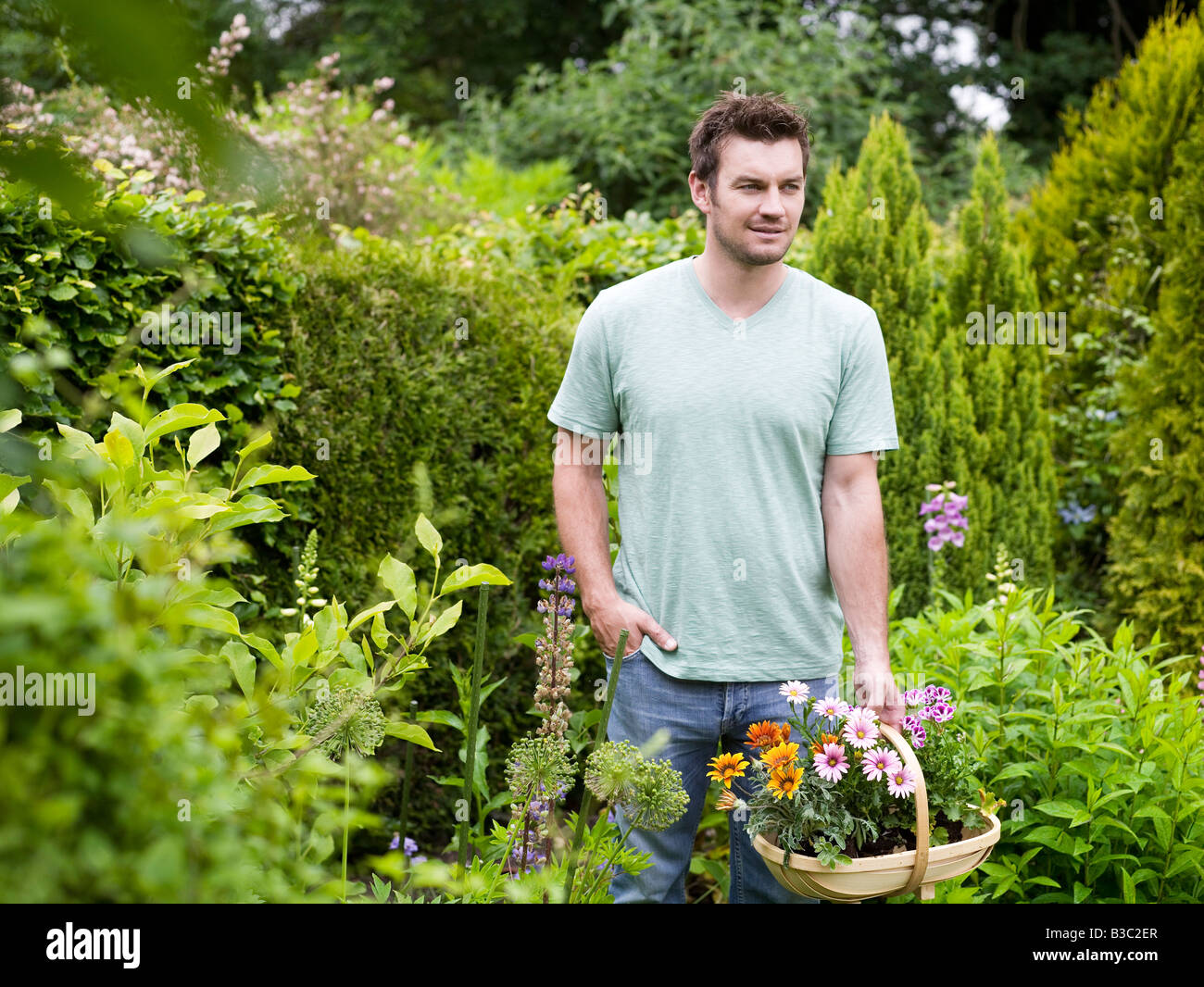A man standing with a basket of flowers in garden Stock Photo, Royalty ...