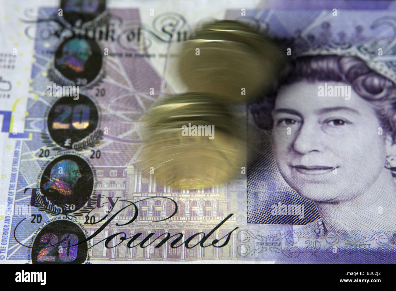 £1 coins rolling over a £20 note Stock Photo - Alamy