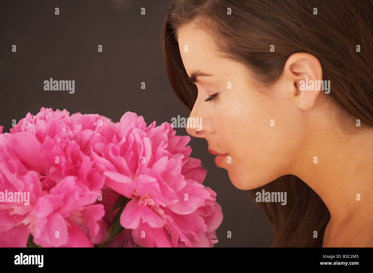 A woman smelling some pink flowers Stock Photo - Alamy