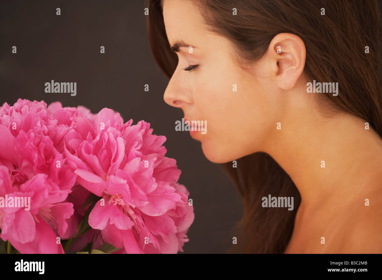 A woman smelling some pink flowers Stock Photo - Alamy
