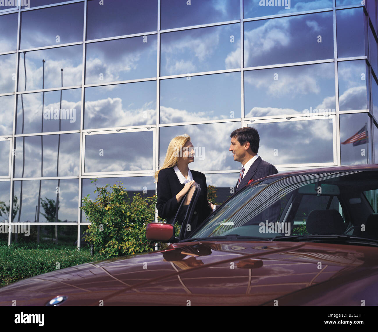 Business people standing with car by office building Stock Photo - Alamy