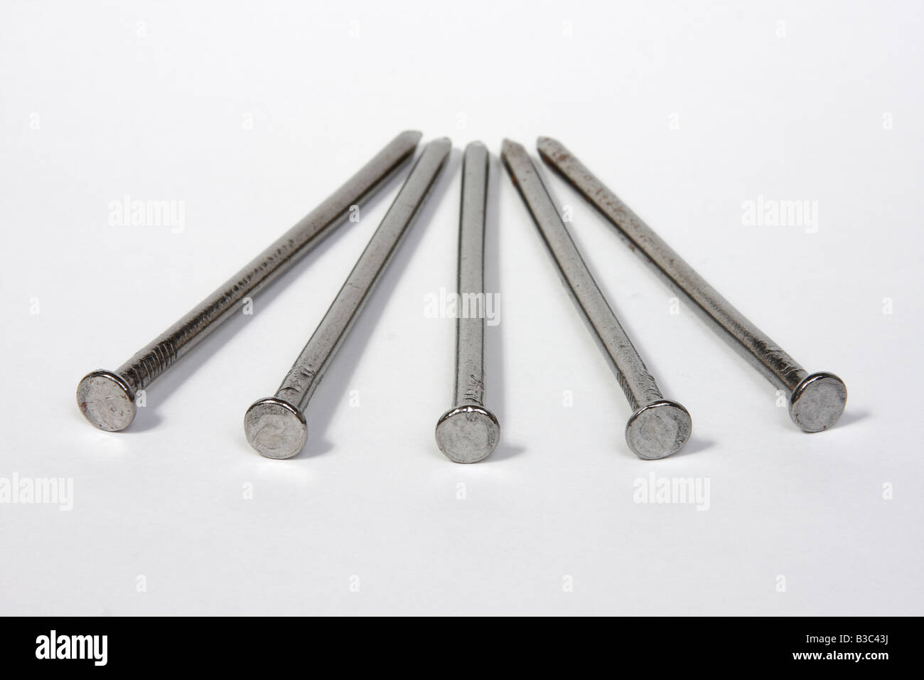 Five large nails on a white background Stock Photo - Alamy