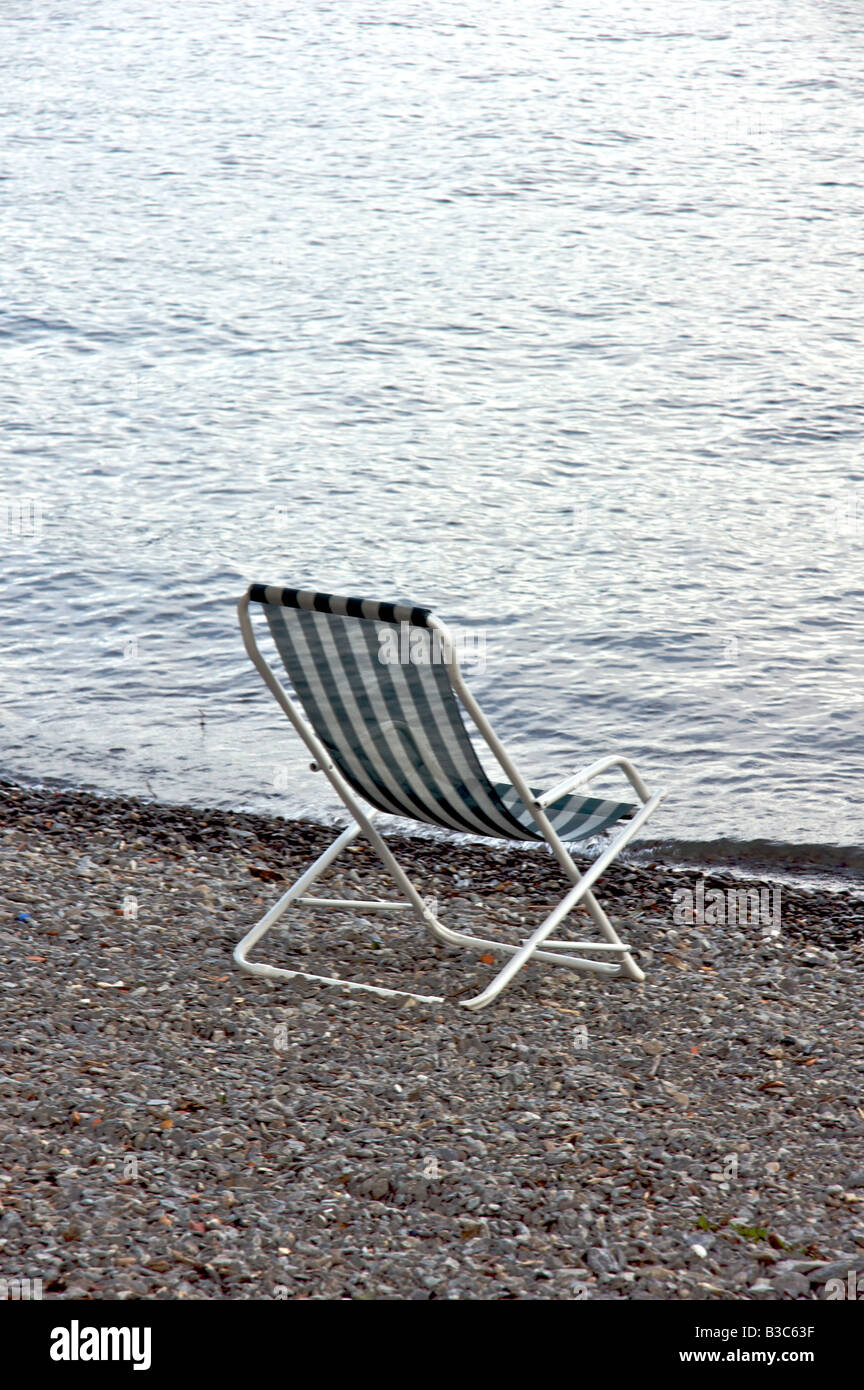 A deck chair on a beach right near the water Stock Photo - Alamy
