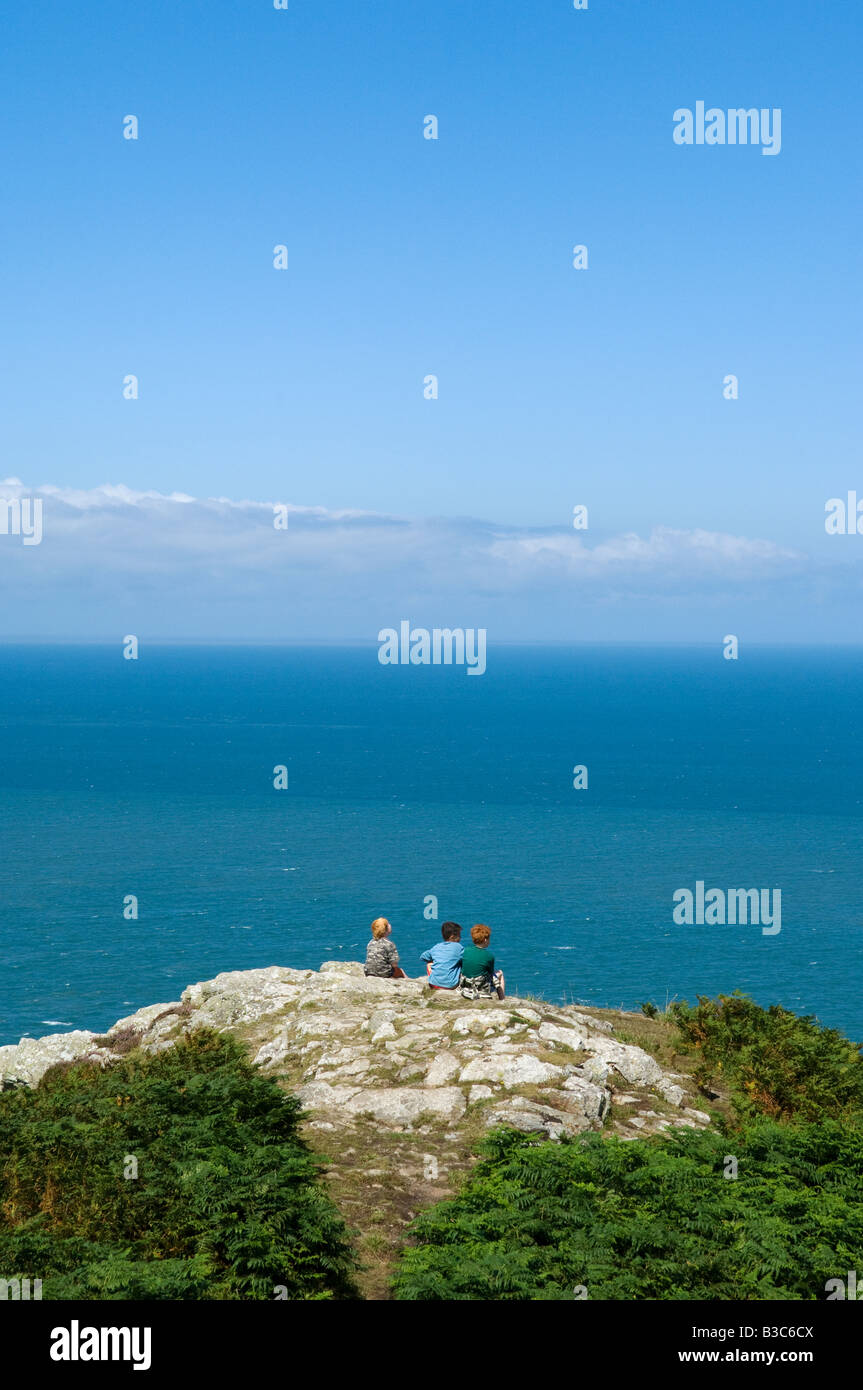 UK, Wales, Pembrokeshire. Three boys sit looking out over Fishguard Bay ...