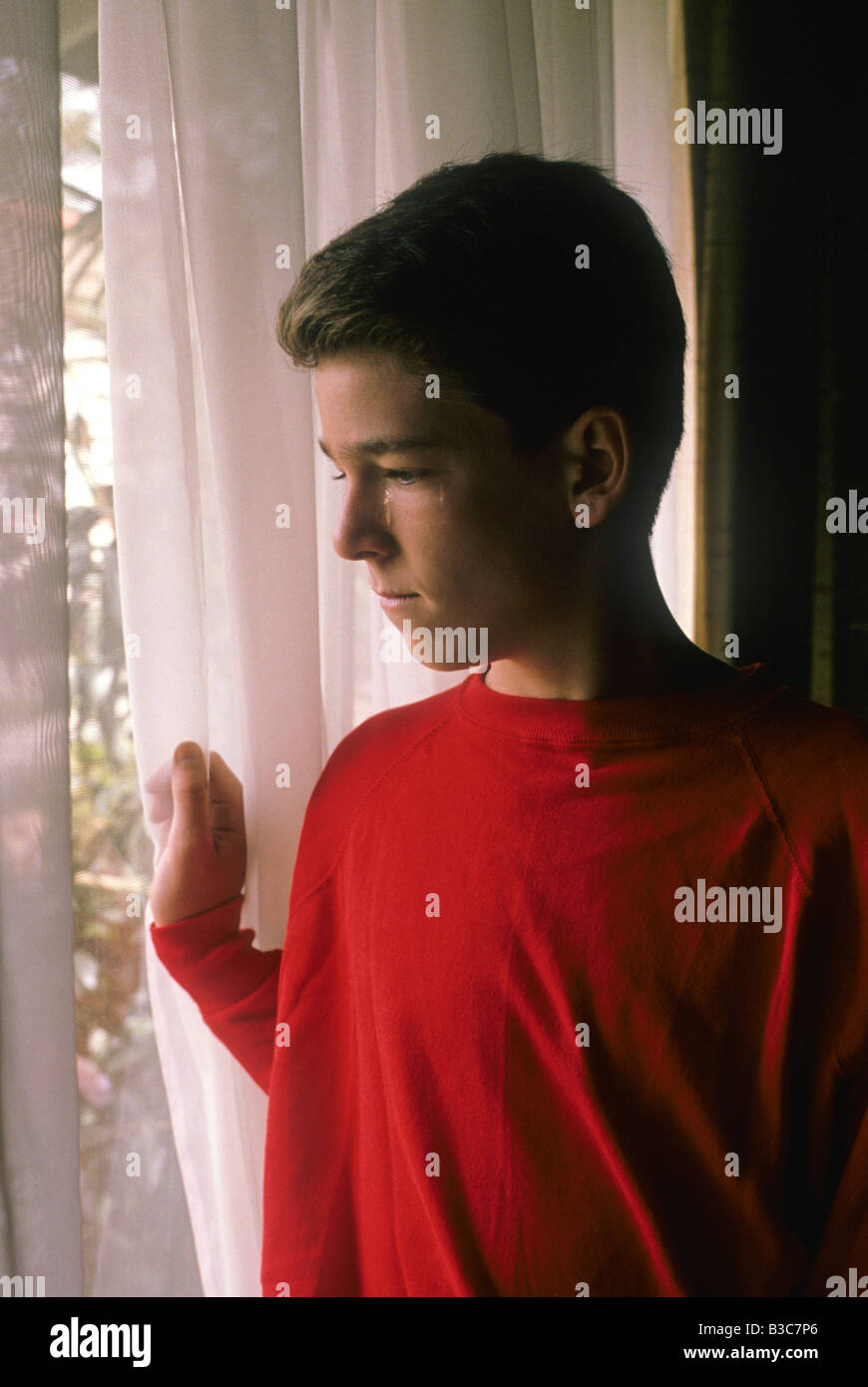 Portrait of teen boy at window with tears in eyes Stock Photo - Alamy