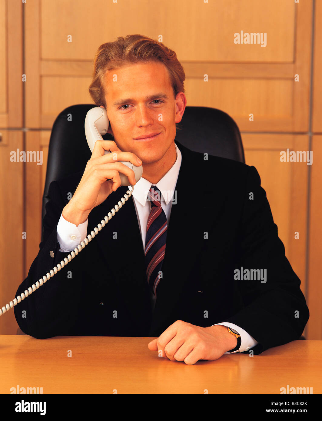 Businessman talking over phone while sitting in office Stock Photo - Alamy