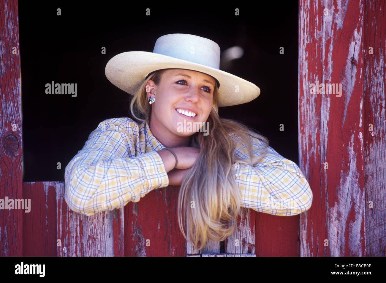 Cowgirl looking through barn window barn Stock Photo - Alamy