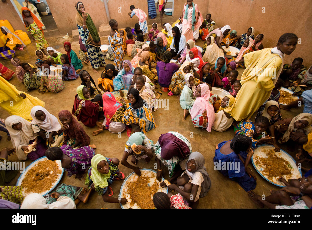 Girls gathered around large plates of food for lunch at the Mame Diarra ...