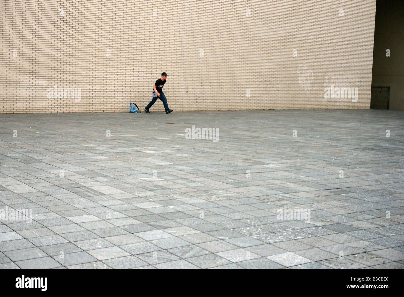 One young underage teenage boy running escaping in front of brick wall ...