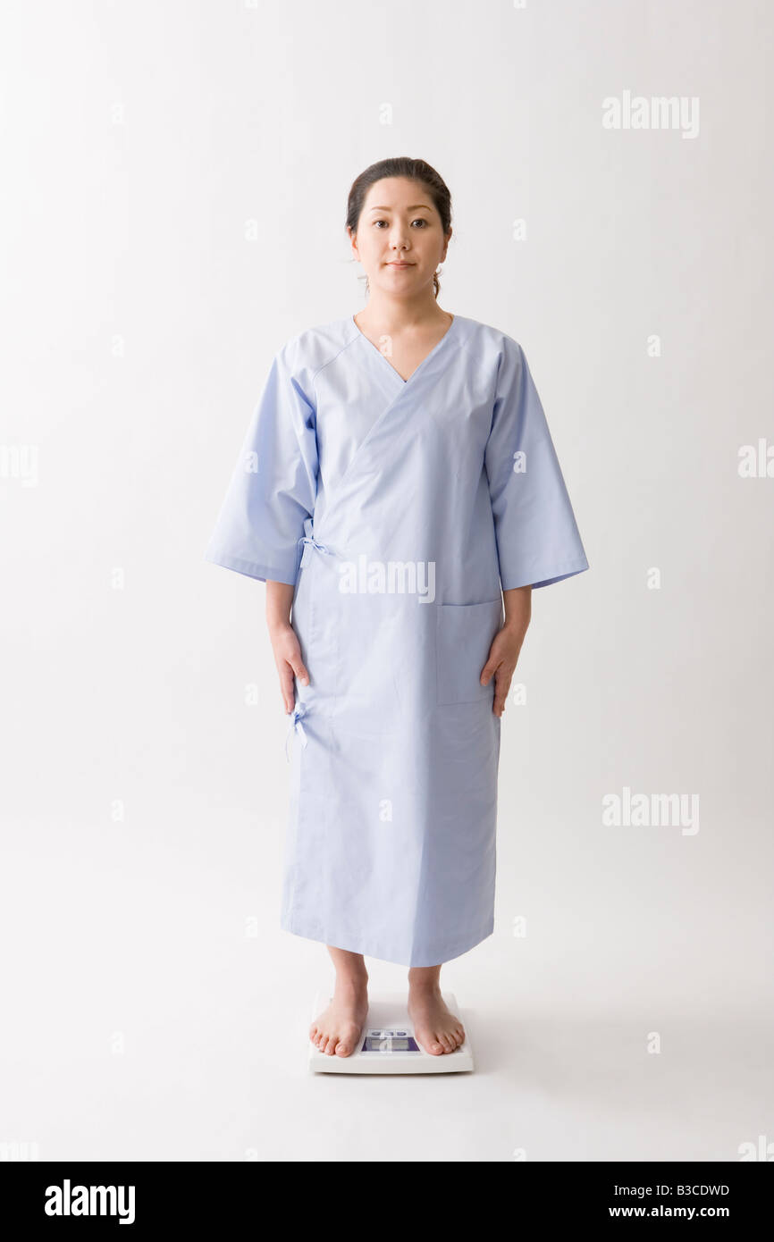 Mid adult woman standing on bathroom scale Stock Photo - Alamy