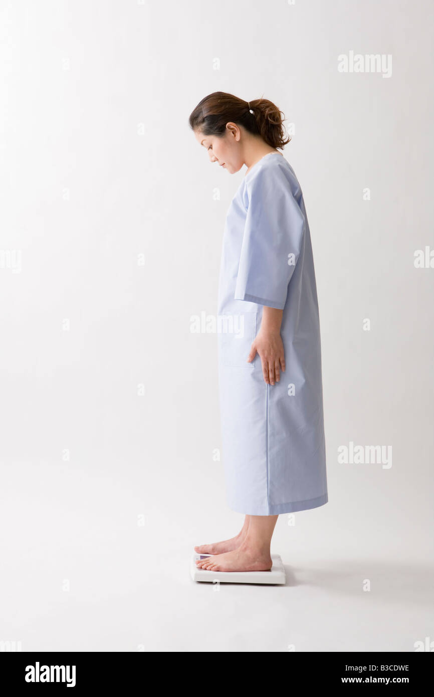 Mid adult woman standing on bathroom scale Stock Photo - Alamy