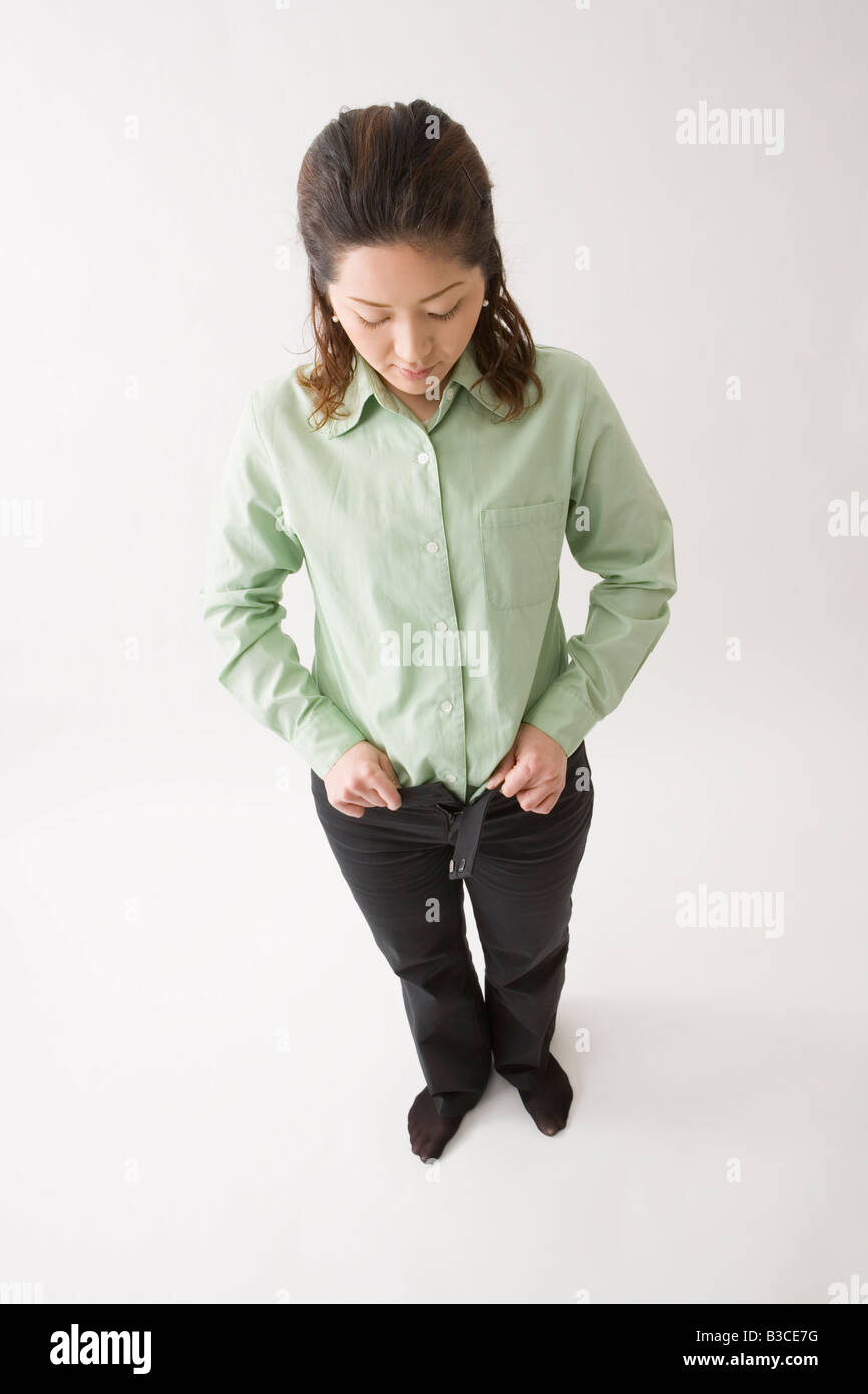 Mid adult woman buttoning pants Stock Photo - Alamy