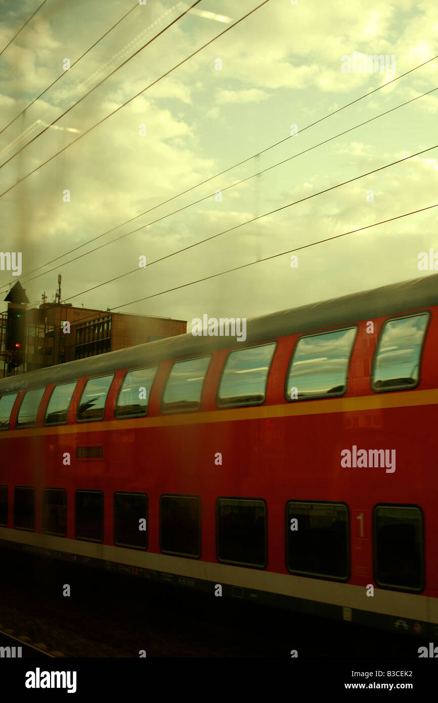 Red German moving train under cloudy sky reflections in windows ...