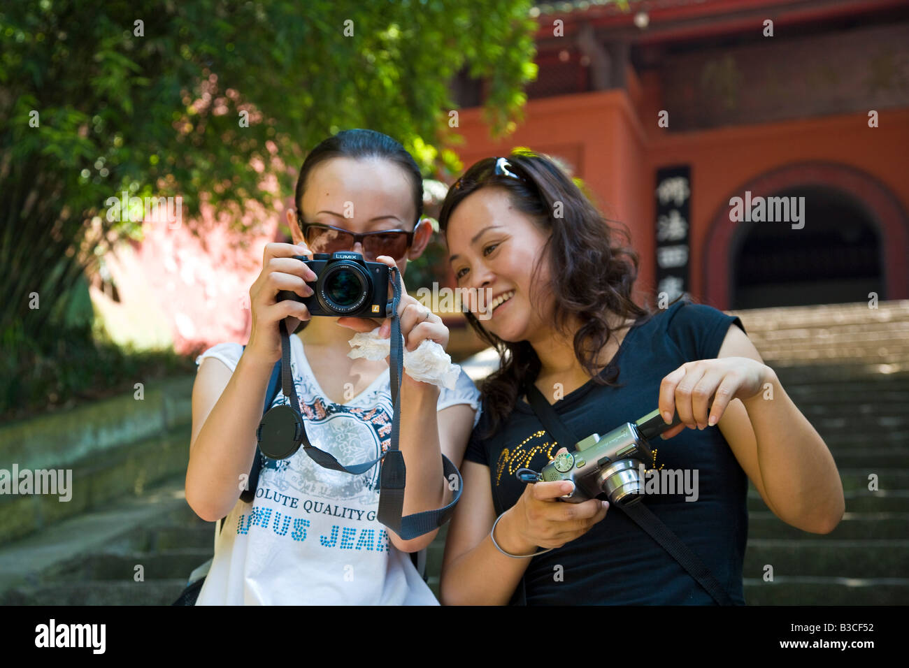 Two young Chinese women look at picture on digital camera in front of ...
