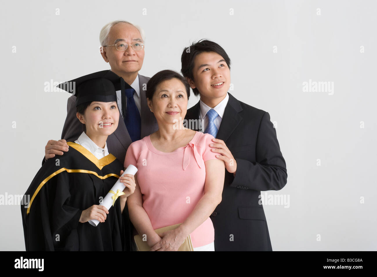 Young female graduate standing with her family and smiling Stock Photo ...