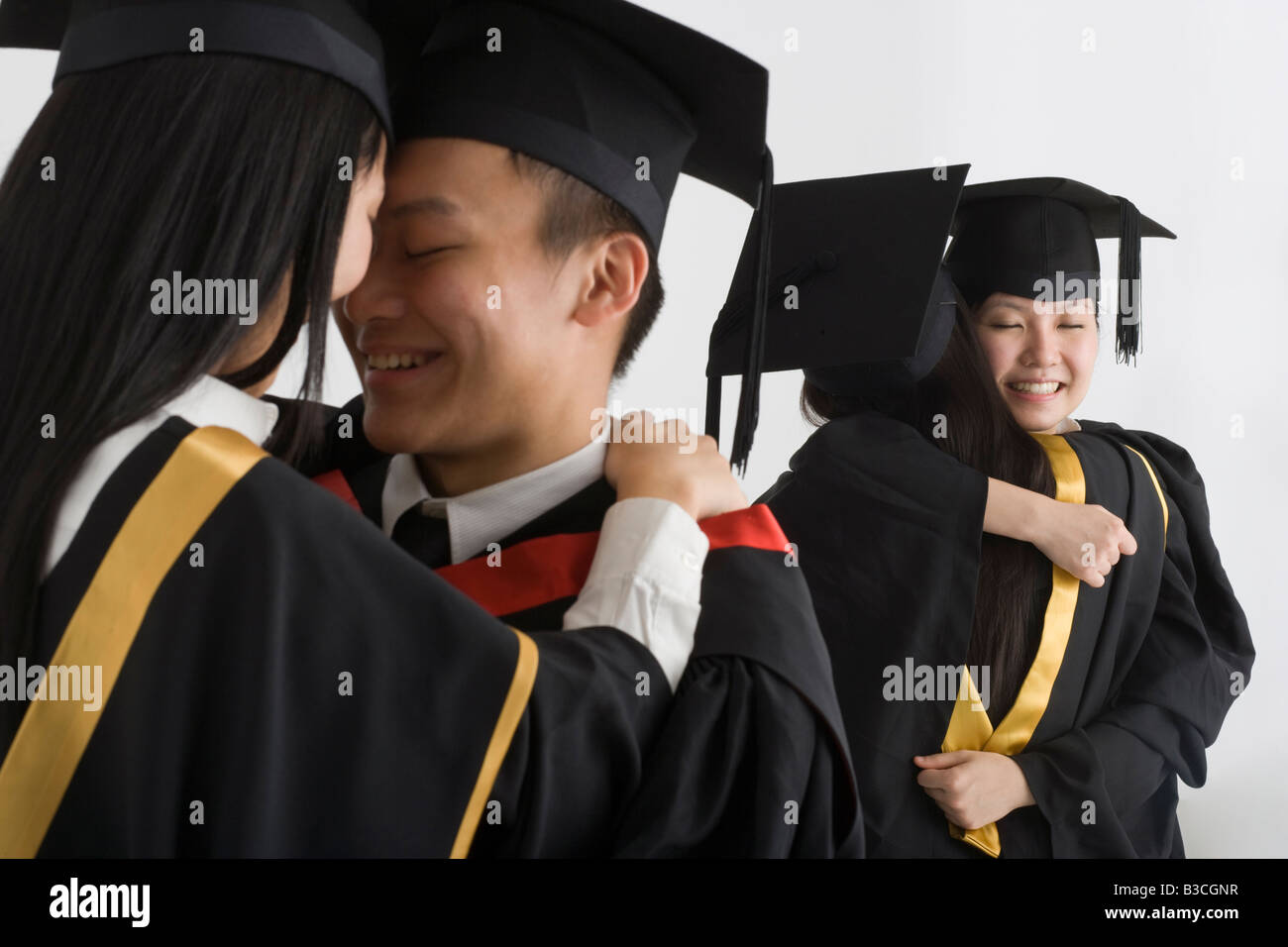 Young male graduate embracing a female graduate and two female ...