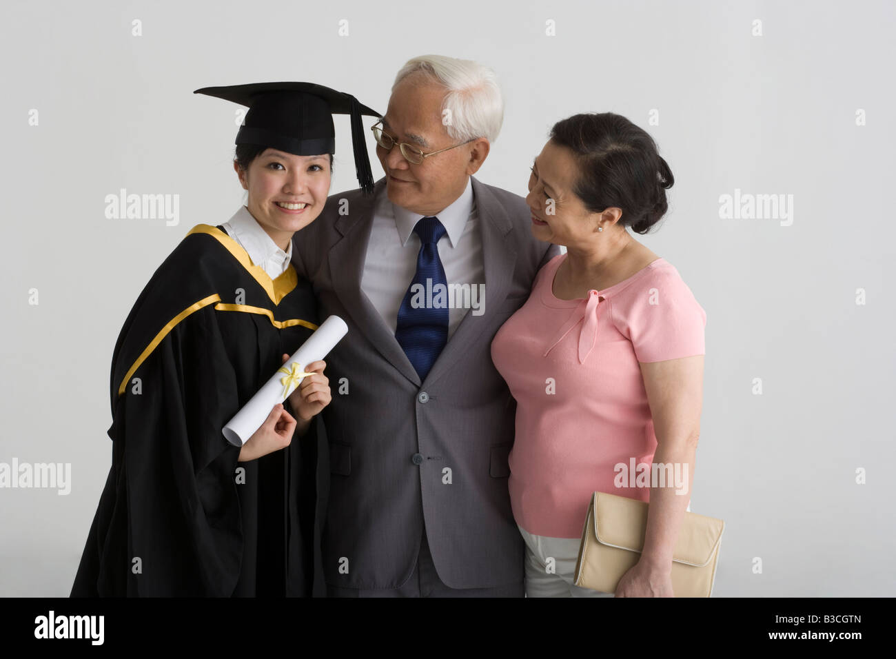 Young female graduate standing with her parents and smiling Stock Photo ...