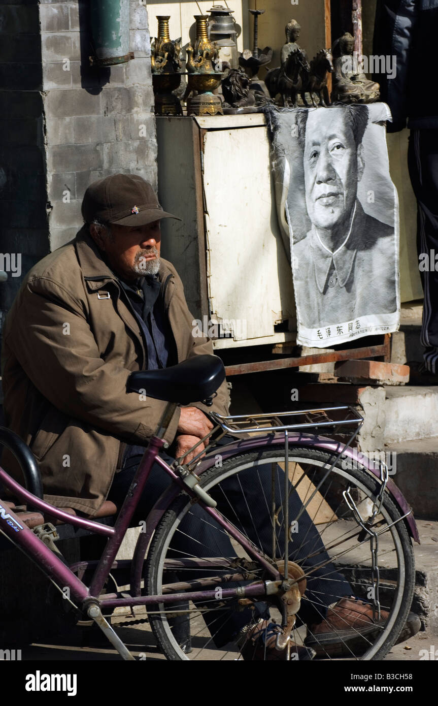 China, Beijing. A man outside an antique shop in a local neighbourhood ...