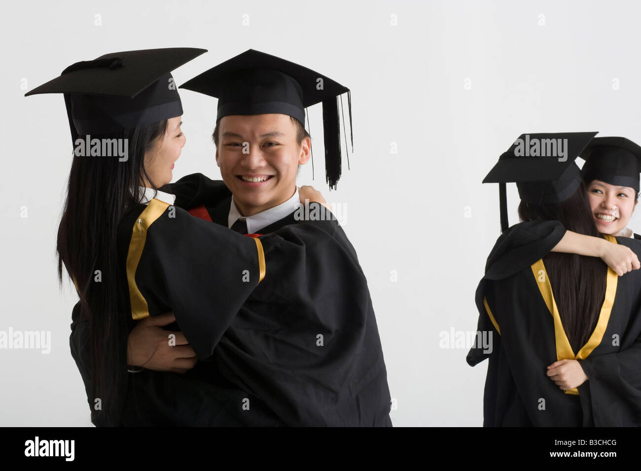 Young male graduate hugging a female graduate and two female graduates ...