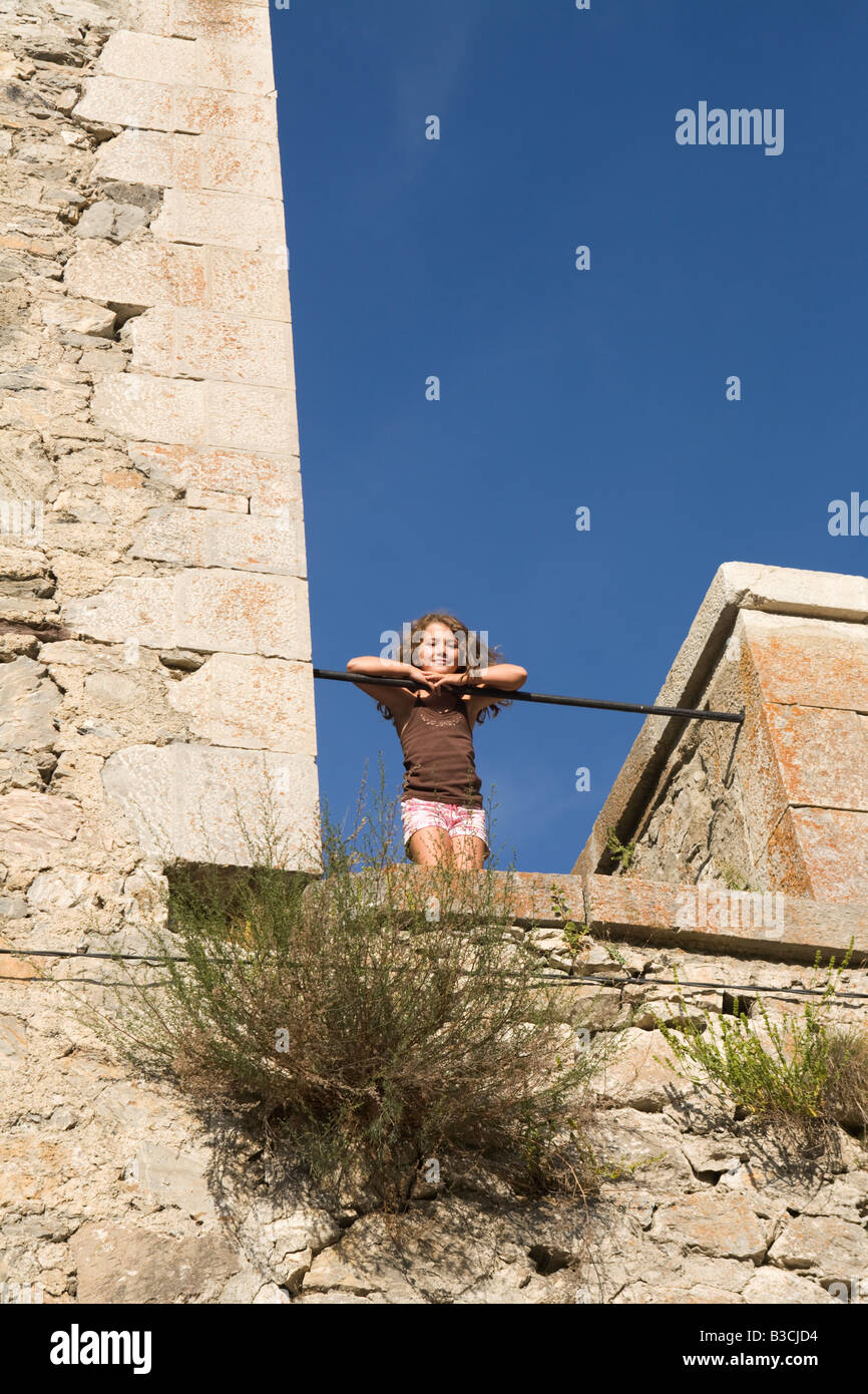 Little girl over the castle wall looking towards the camera smiling ...
