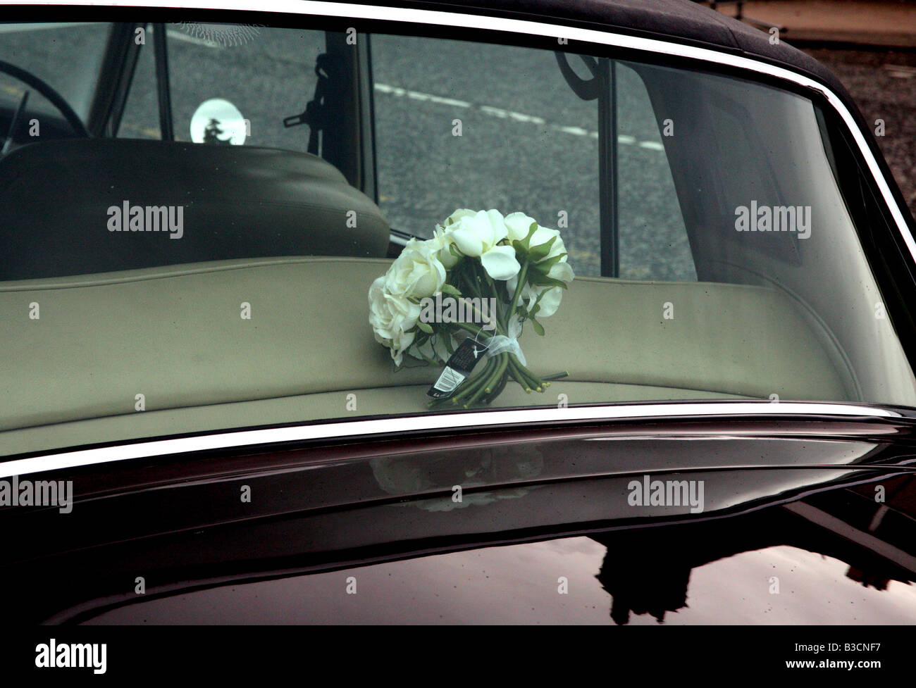 Bouquet on rear window shelf of wedding car Stock Photo - Alamy
