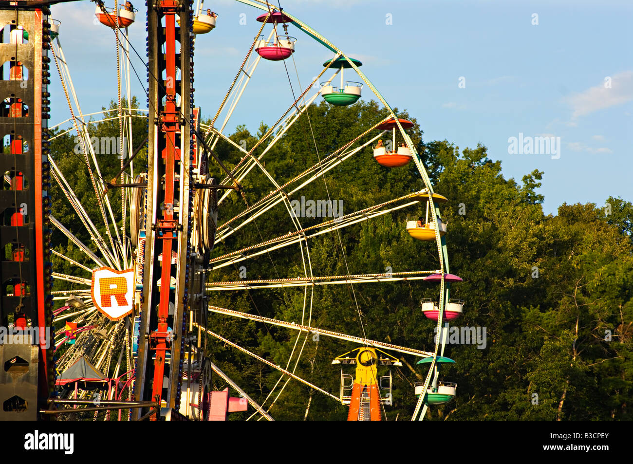 Ferris wheel and loop the loop carnival rides with trees and blue sky ...