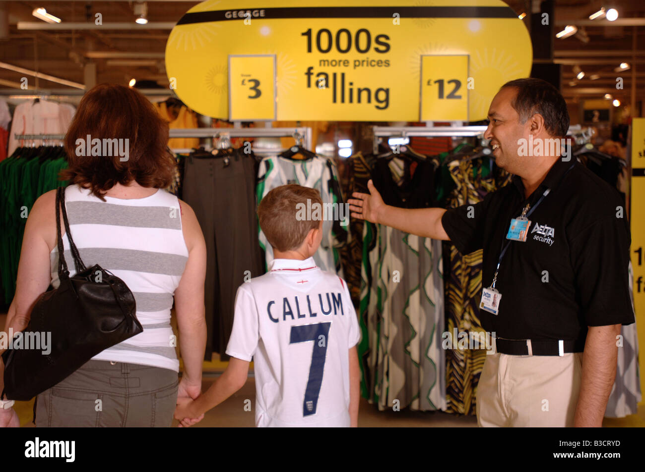 A SECURITY GUARD DIRECTS SHOPPERS INTO A SUPERMARKET CLOTHING SECTION ...