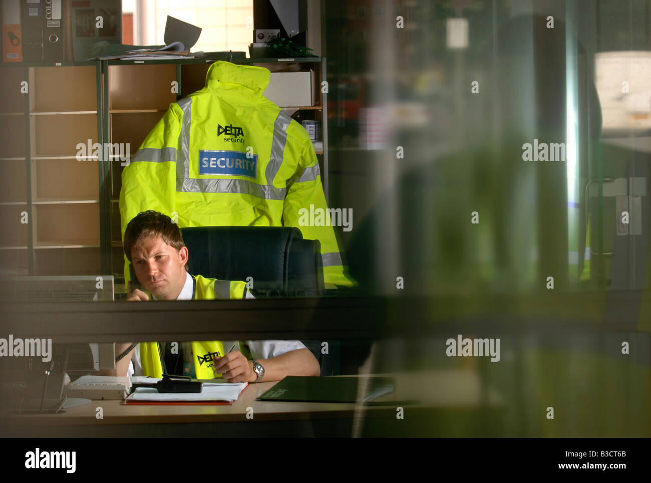 A SECURITY GUARD LOGS INFORMATION AT AN OFFICE DESK UK Stock Photo - Alamy